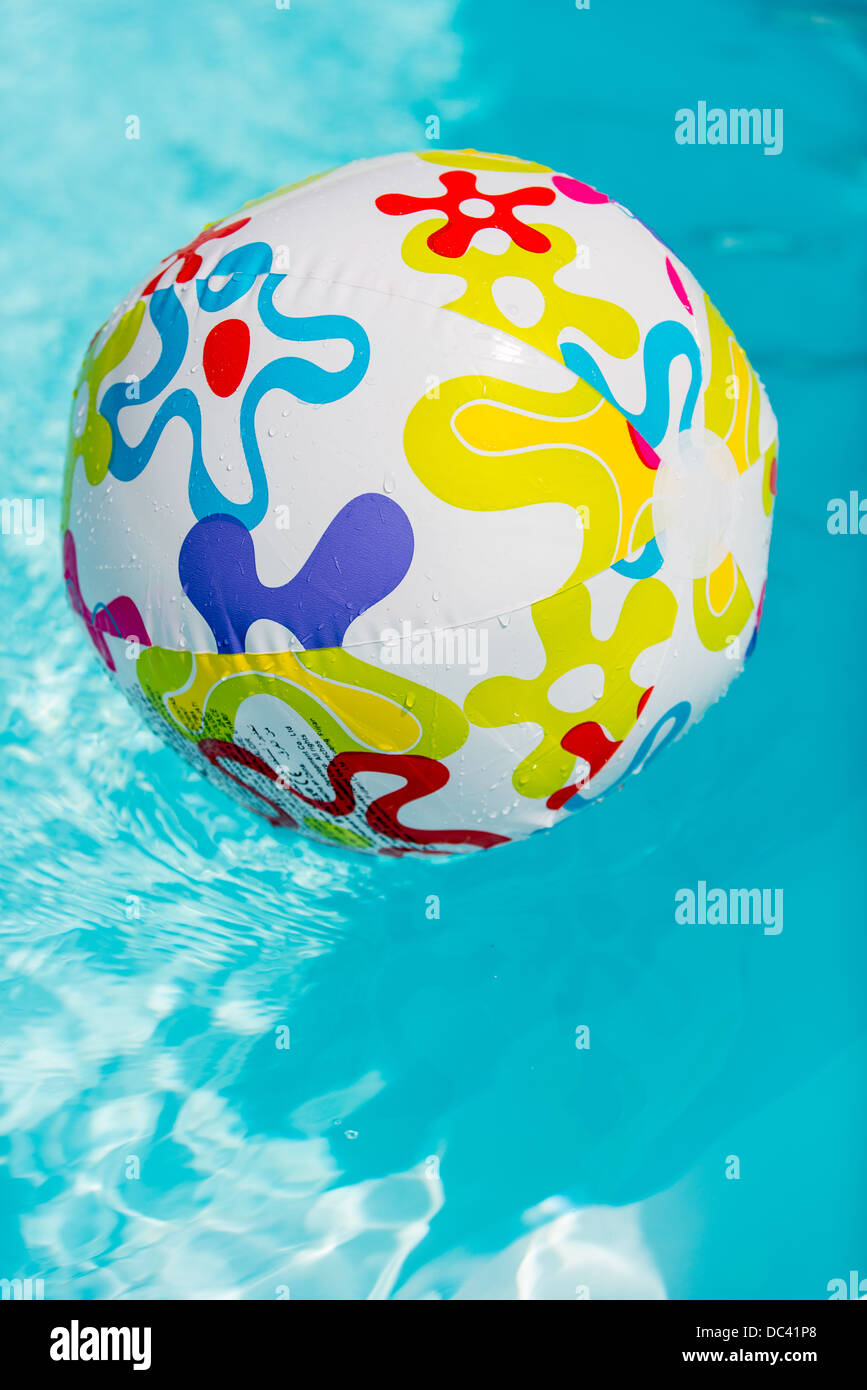Colorful beach ball floating on water of swimming pool Stock Photo - Alamy