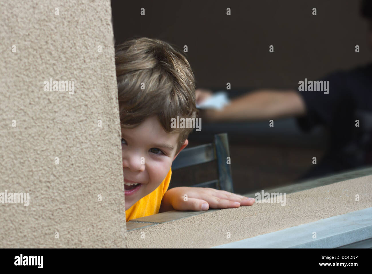 A young boy with a cute smile leaning out a window Stock Photo - Alamy