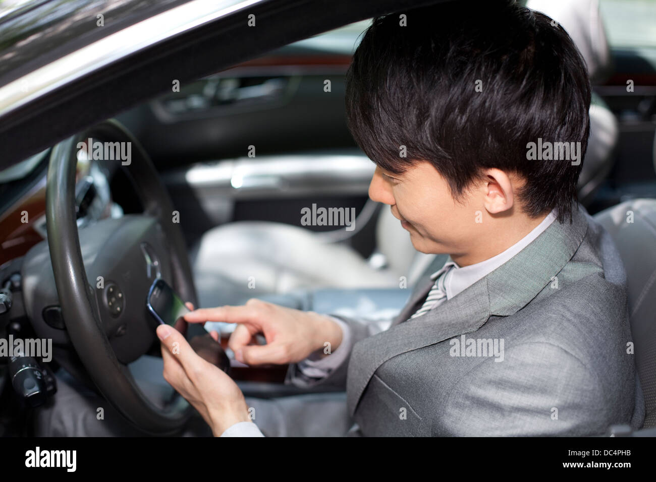 Businessman playing mobile phone inside car Stock Photo - Alamy