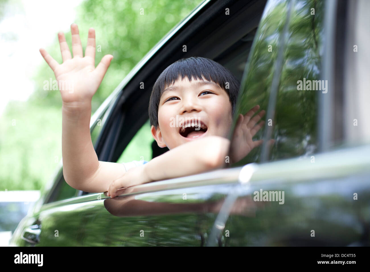 Cheerful boy waving out of car window Stock Photo - Alamy