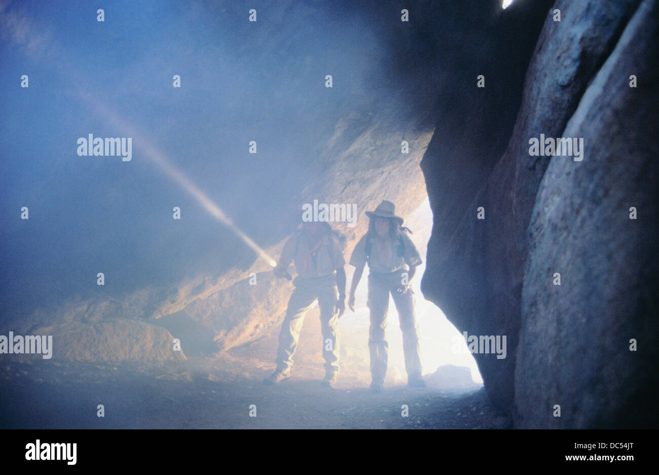 Men walking into dark cave with flashlights Stock Photo - Alamy