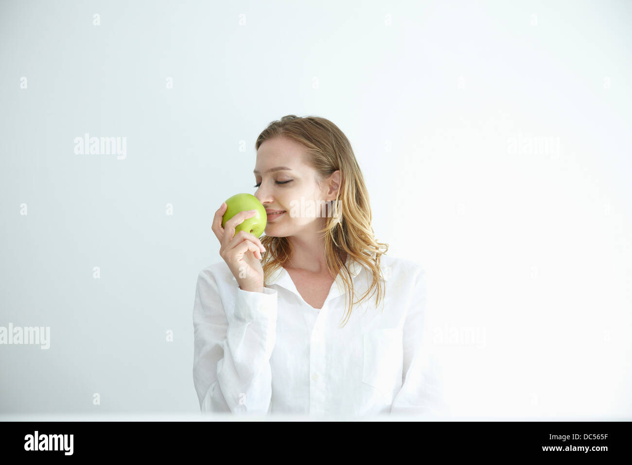 lady in white shirt smelling an apple Stock Photo - Alamy