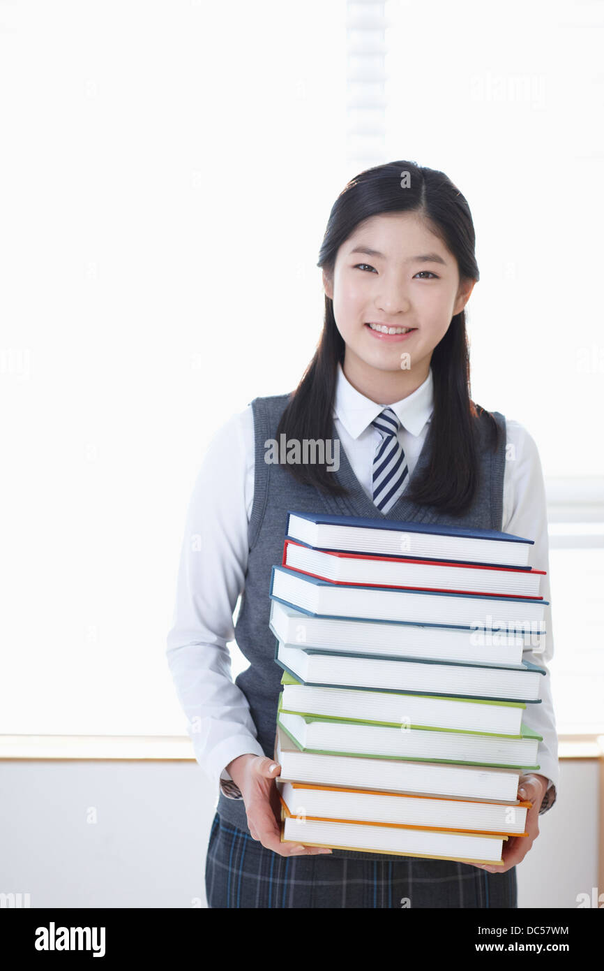 student in school uniform holding a pile of books Stock Photo - Alamy