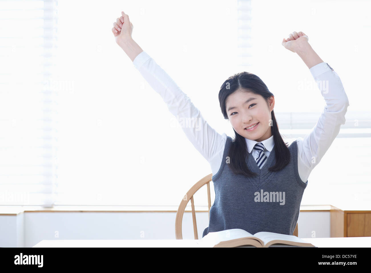 student in school uniform stretching while sitting at desk Stock Photo ...