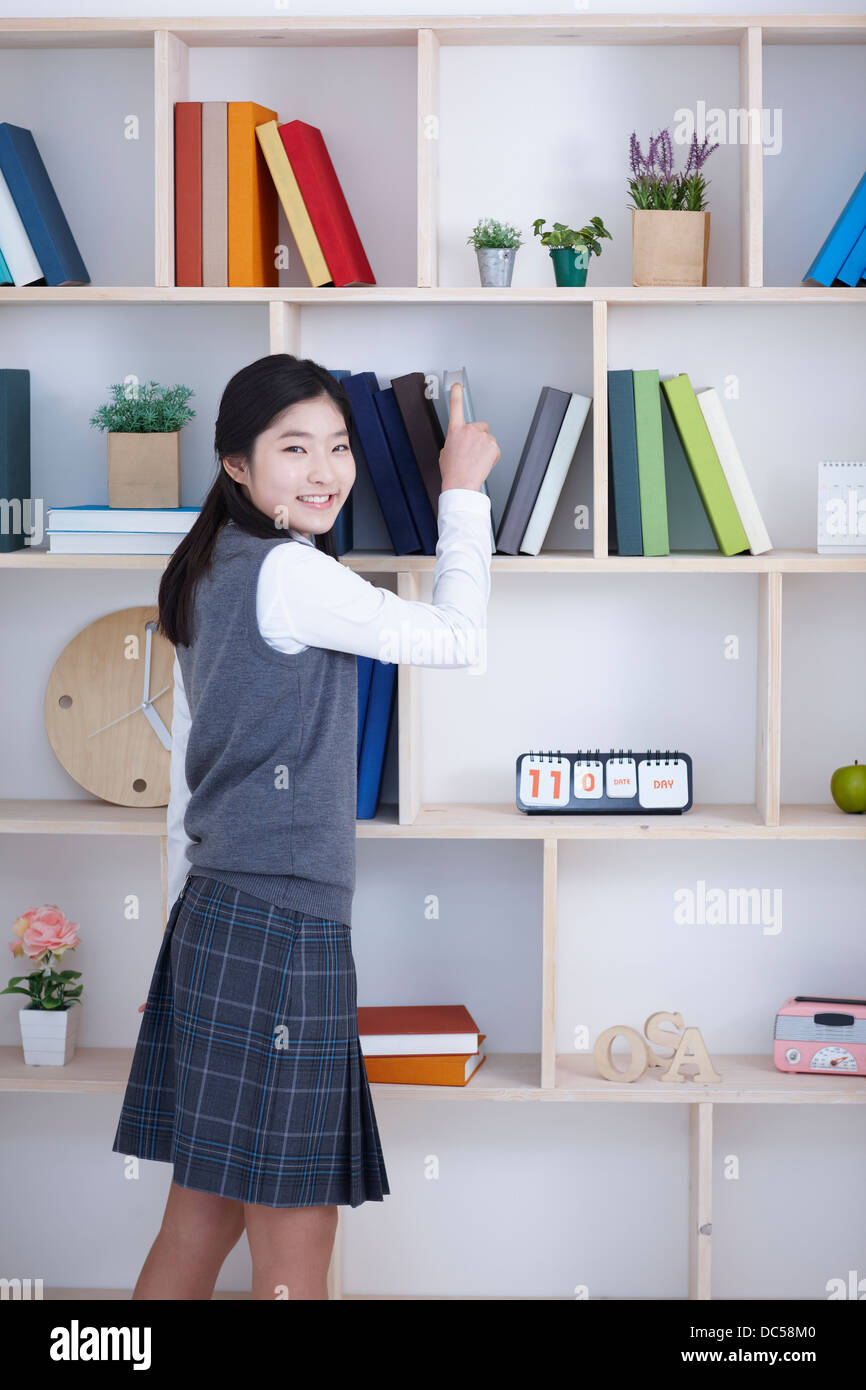 student in school uniform choosing a book from a bookshelf Stock Photo ...