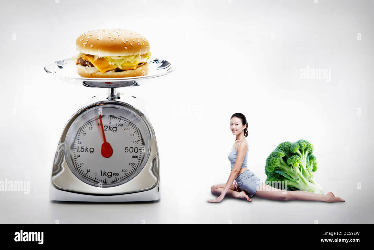 a woman stretching next to a scale with hamburger Stock Photo - Alamy