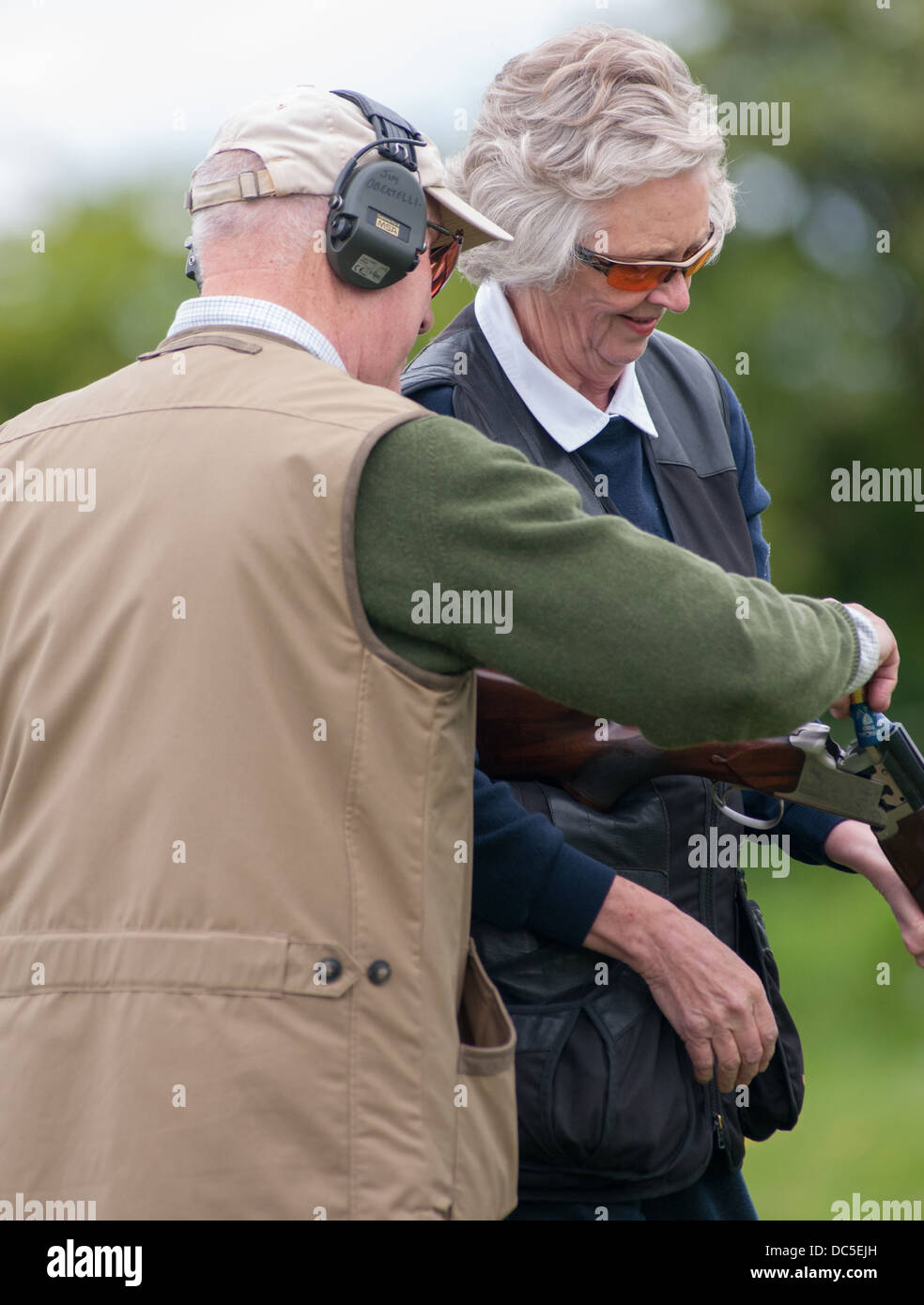 Lady shooting a shotgun at a simulated game clay shooting day, helped ...