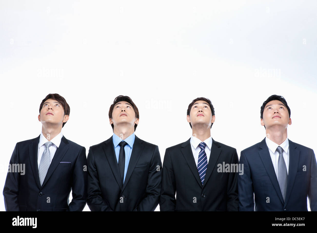 four businessmen looking up while standing in a line Stock Photo - Alamy