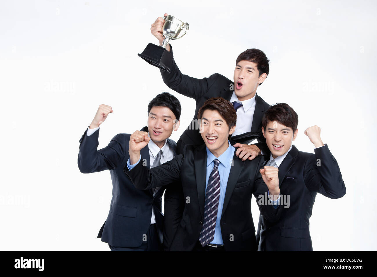 businessmen cheering with one holding trophy Stock Photo - Alamy