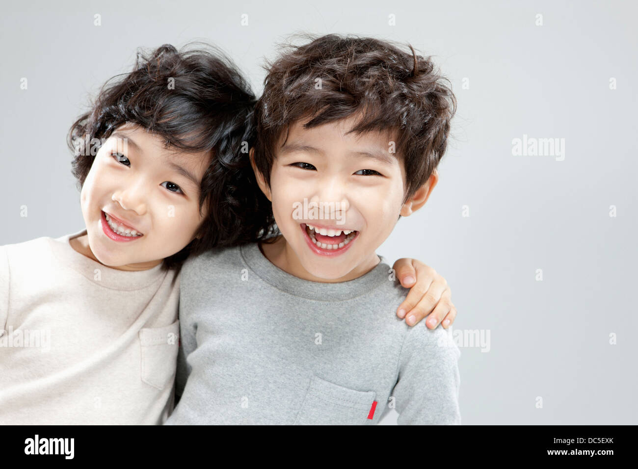 two boys together in grey background Stock Photo - Alamy