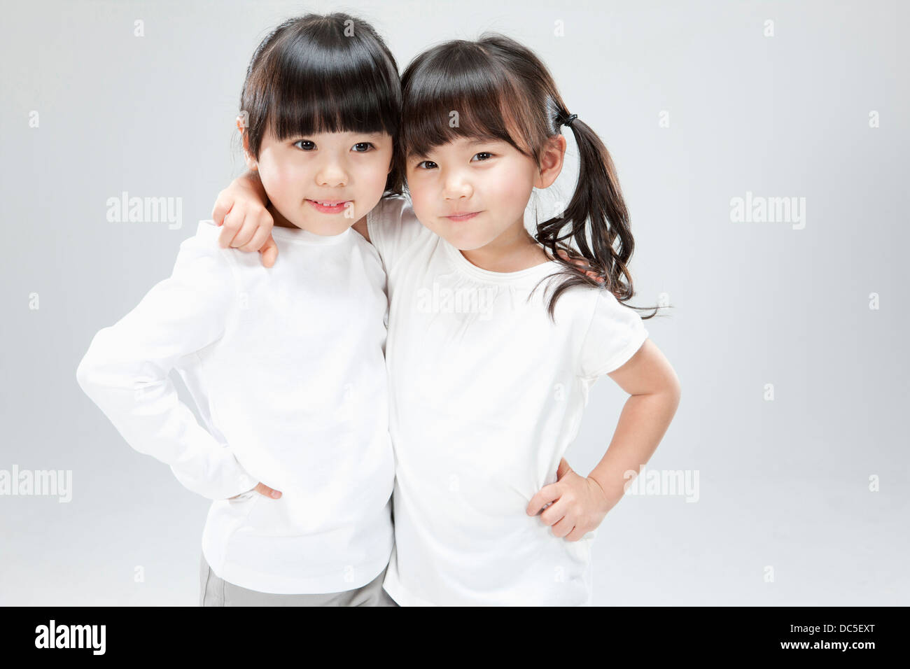 two girls together in grey background Stock Photo - Alamy