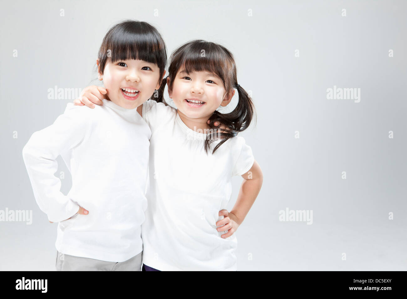 two girls together in grey background Stock Photo - Alamy