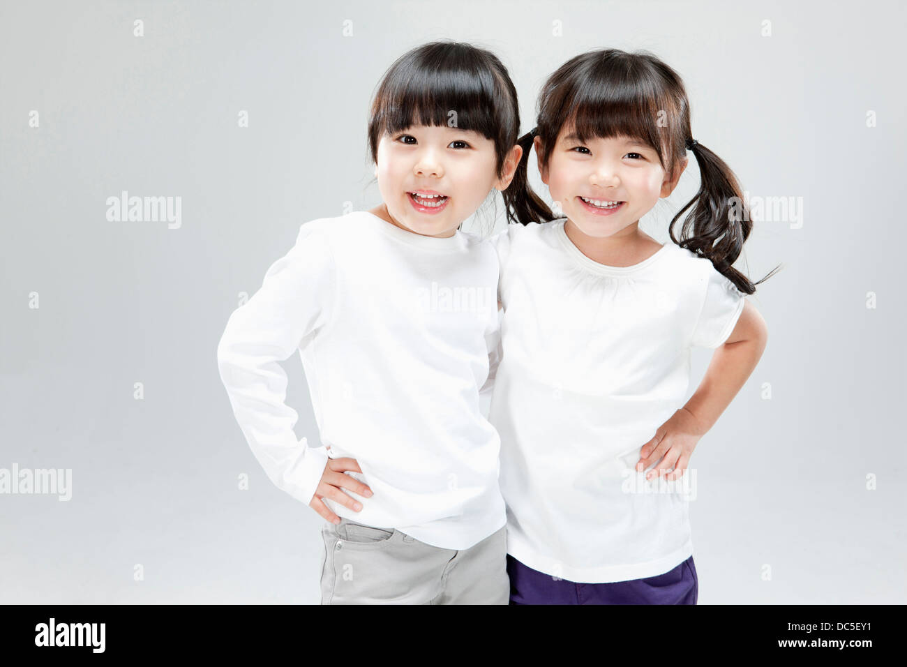 two girls together in grey background Stock Photo - Alamy