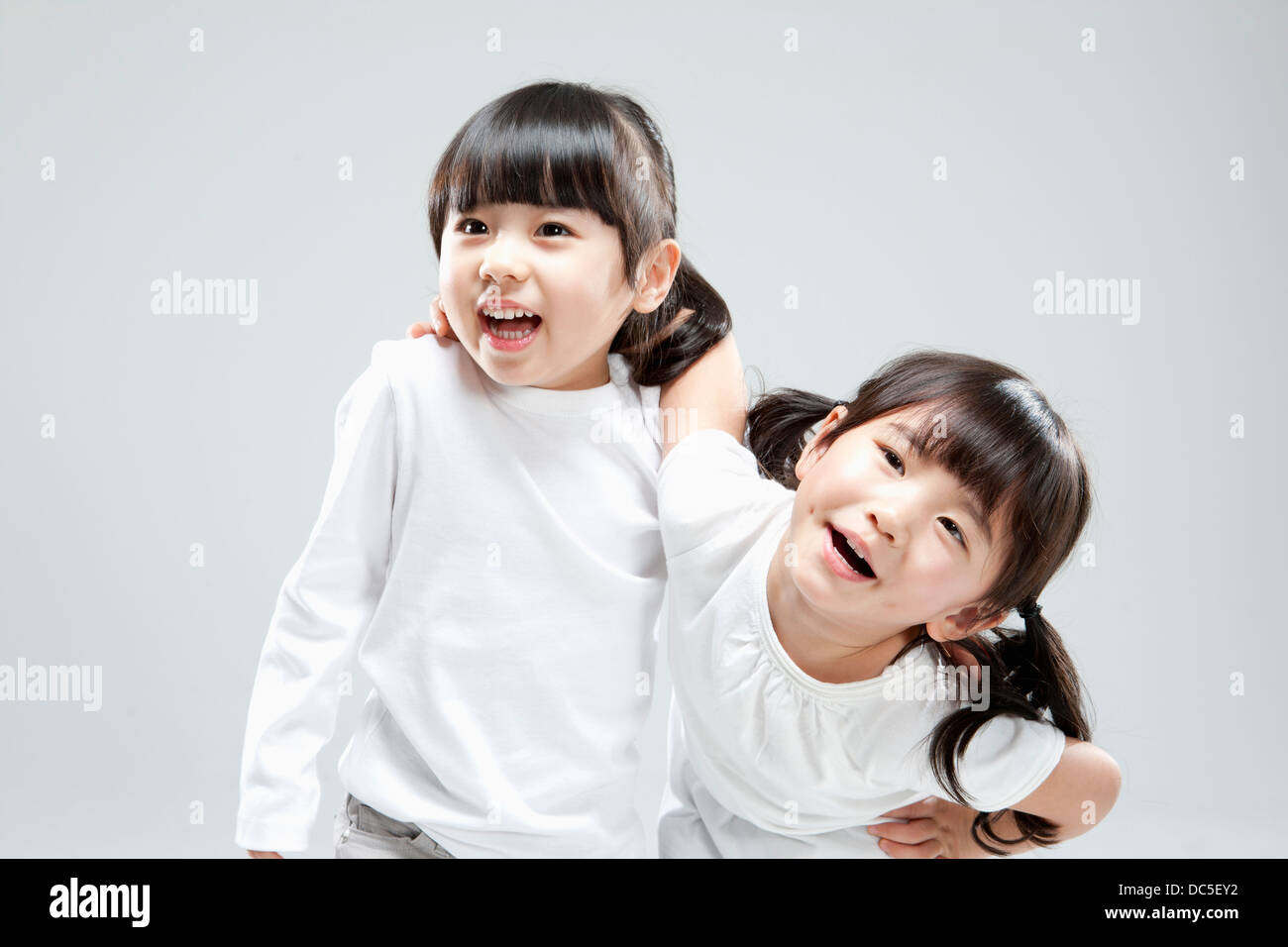 two girls together in grey background Stock Photo - Alamy