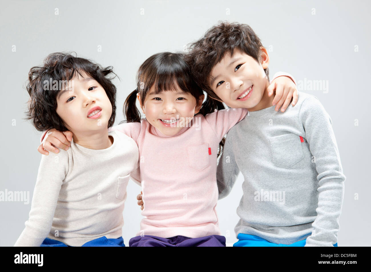 kids posing arms around each other in grey background Stock Photo - Alamy