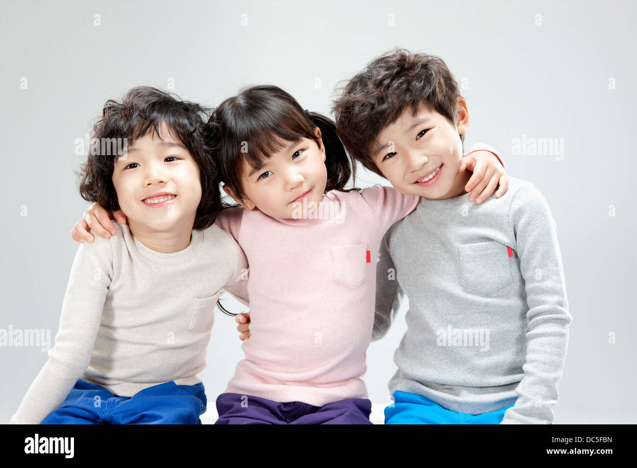 kids posing arms around each other in grey background Stock Photo - Alamy