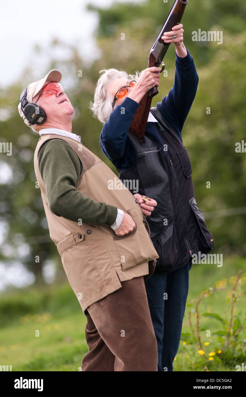 Lady shooting a shotgun at a simulated game clay shooting day, helped ...