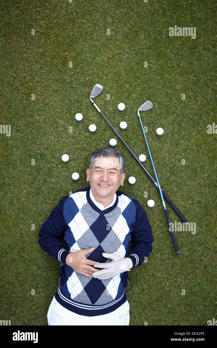 middle aged man lying on golf field with golf balls and clubs Stock ...