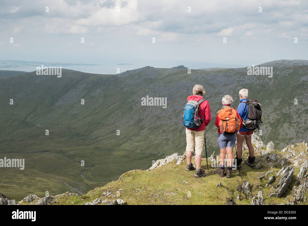 Three hikers hiking on Yr Elen mountain looking at a view from ...