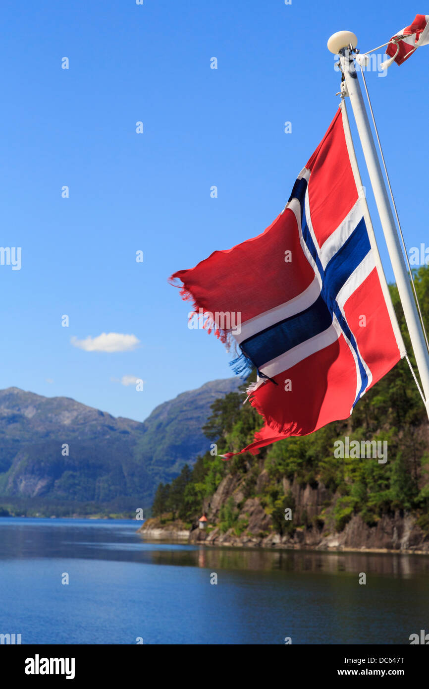 Norwegian flag flying on a boat cruise sailing along Osterfjorden fjord ...