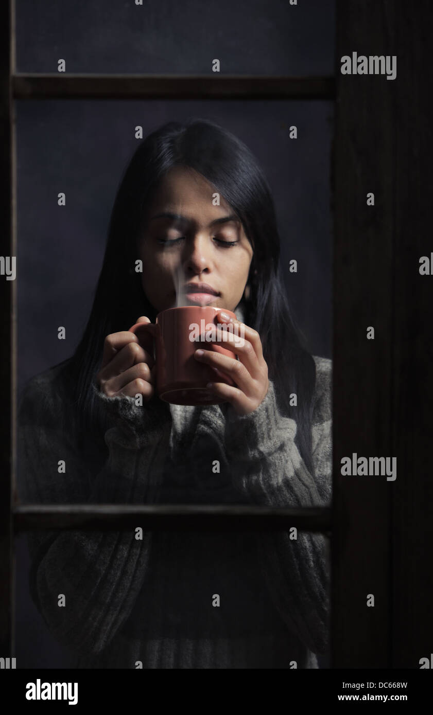 Young woman behind window with a cup of coffee or tea Stock Photo - Alamy