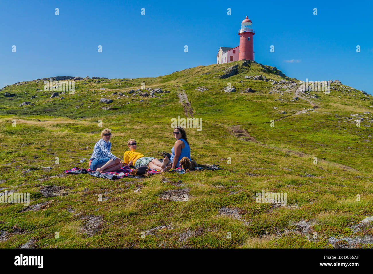 Canadians, two women and one man in their twenties, picnic outside on ...