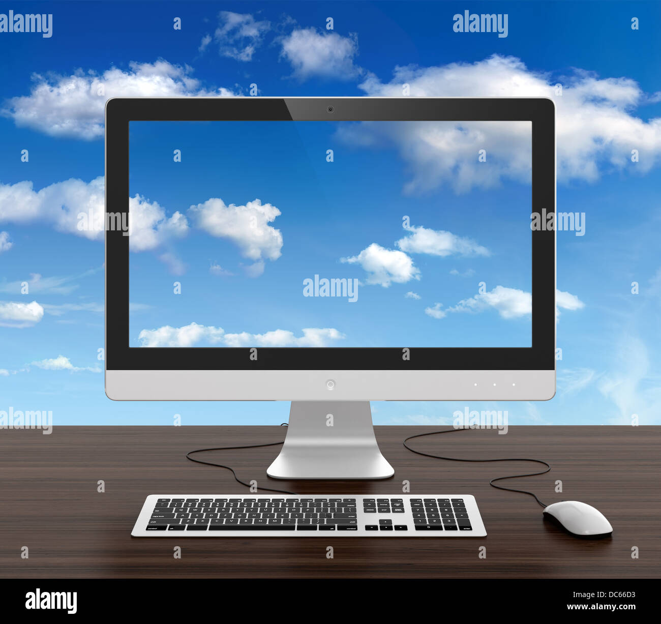 Computer monitor with keyboard and mouse on desk and cloudy sky on ...