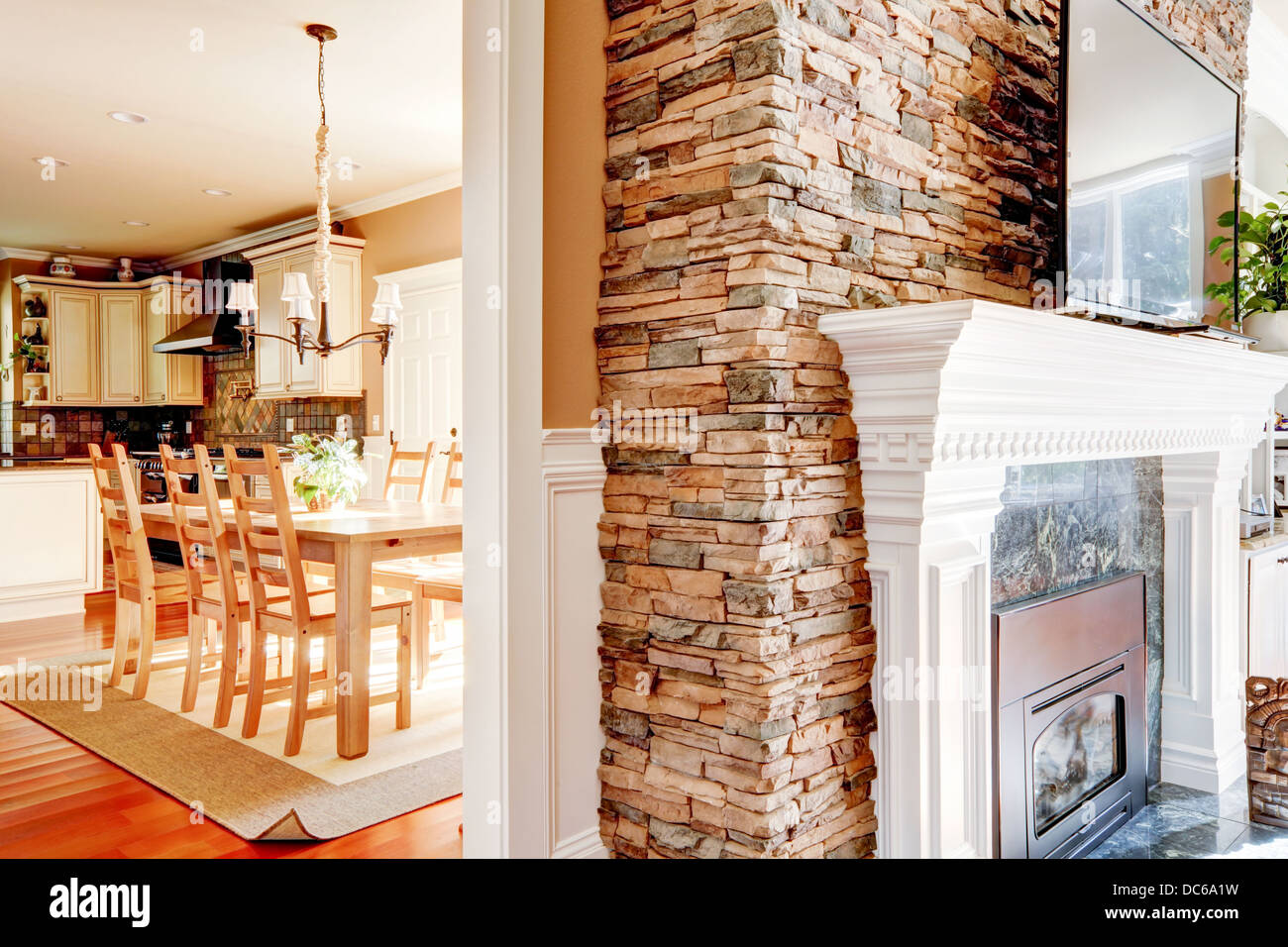 Stone fireplace with tv and dining room and kitchen Stock Photo - Alamy