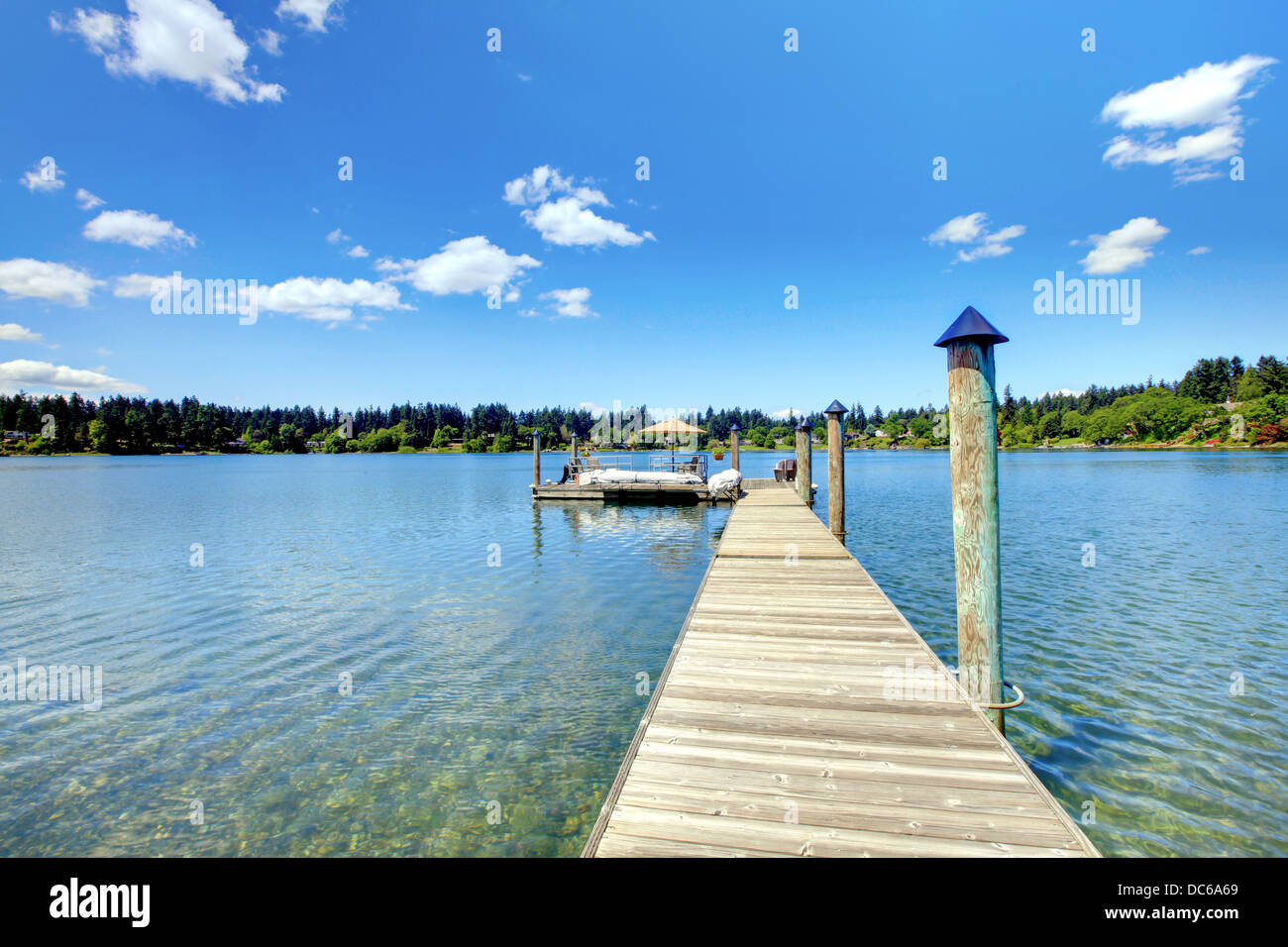 Lake with long wood pier and private party raft Stock Photo - Alamy