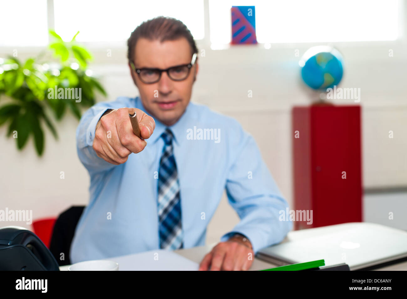 Serious manager pointing at you from his work desk Stock Photo - Alamy