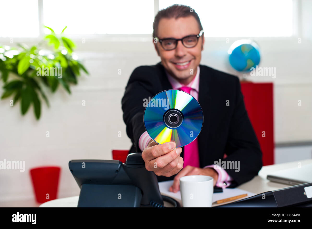 Bespectacled boss presenting a compact disk Stock Photo - Alamy