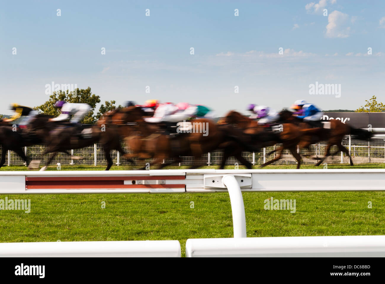 The blur of racehorses racing by the rails on a race track Stock Photo ...