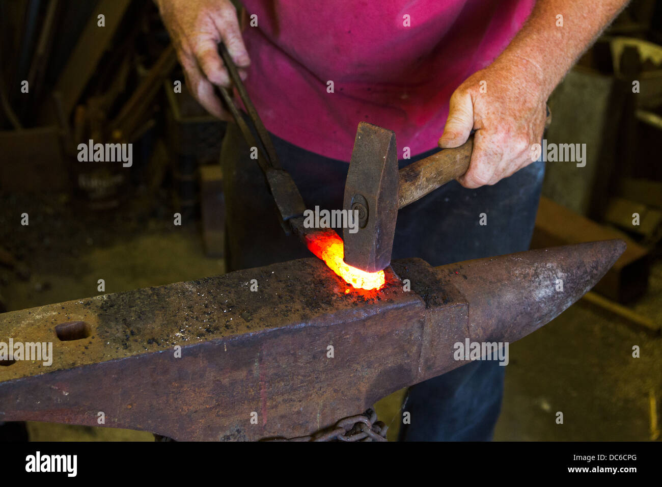 Blacksmith beating white hot iron with hammer on anvil Stock Photo - Alamy