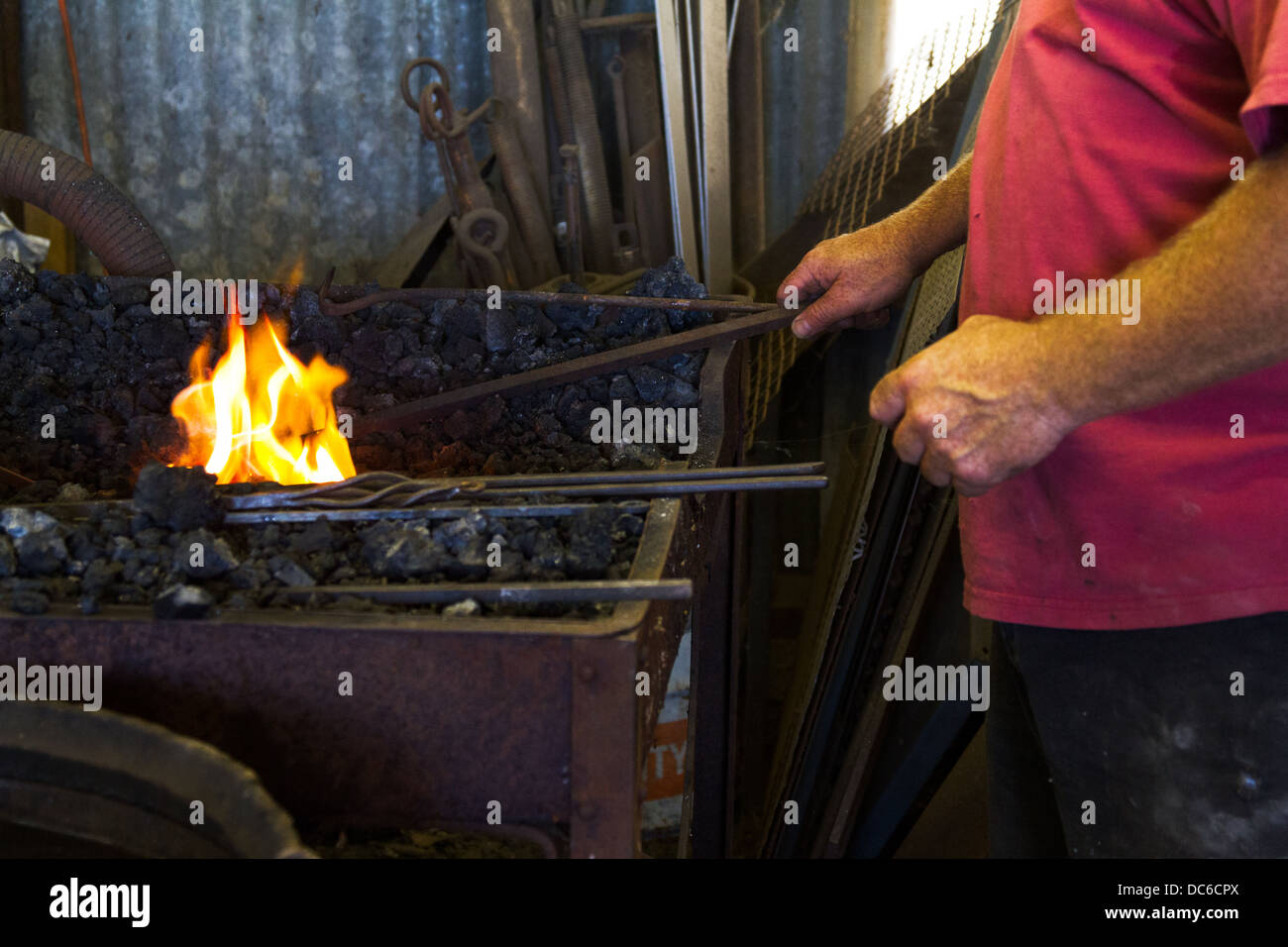 Blacksmith heating a piece of iron in hot coals Stock Photo - Alamy