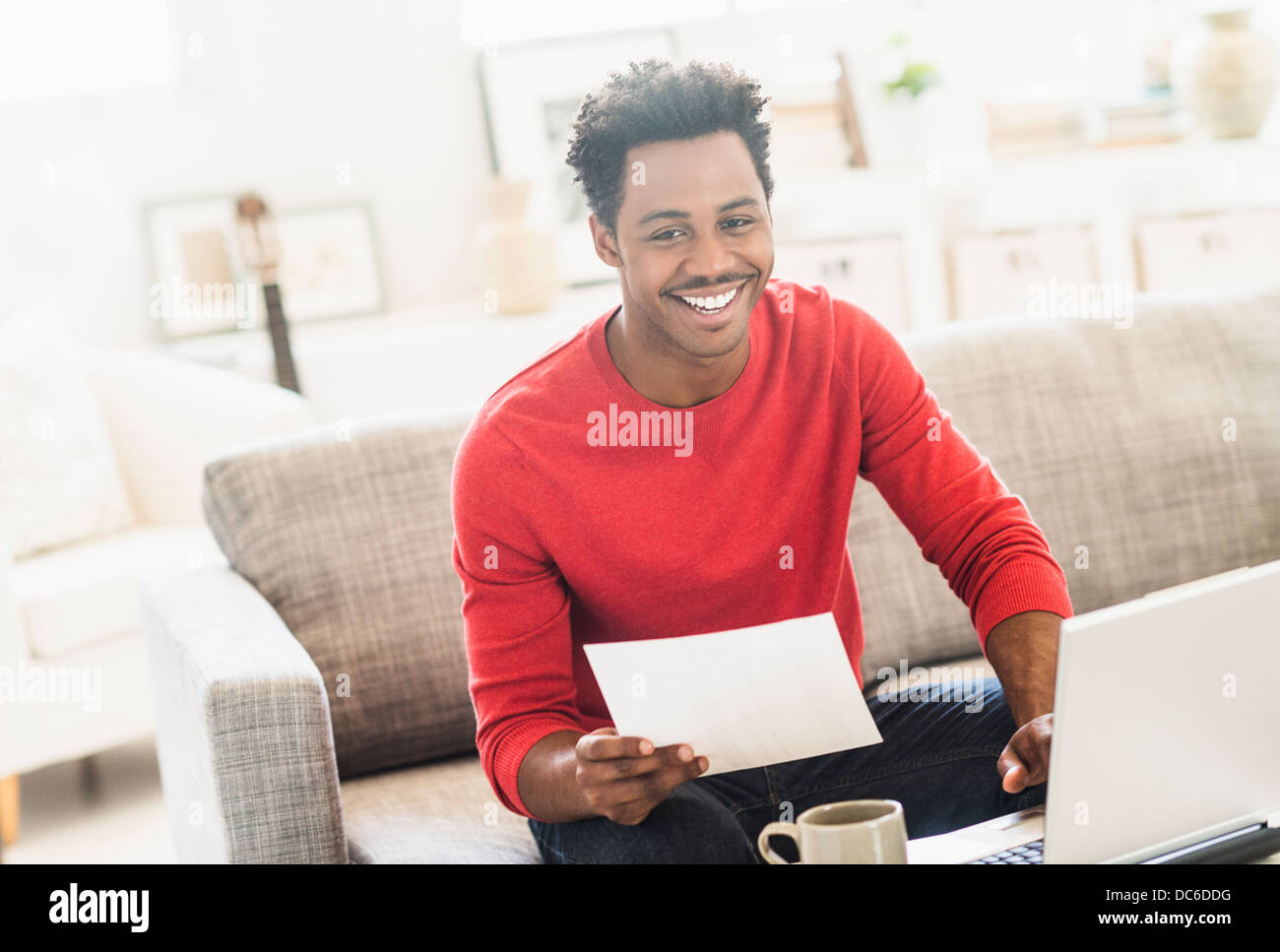Man sitting on sofa and using laptop Stock Photo - Alamy