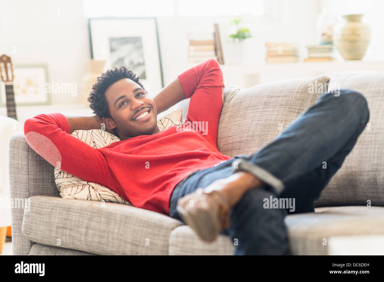 Man lying on sofa and smiling Stock Photo - Alamy