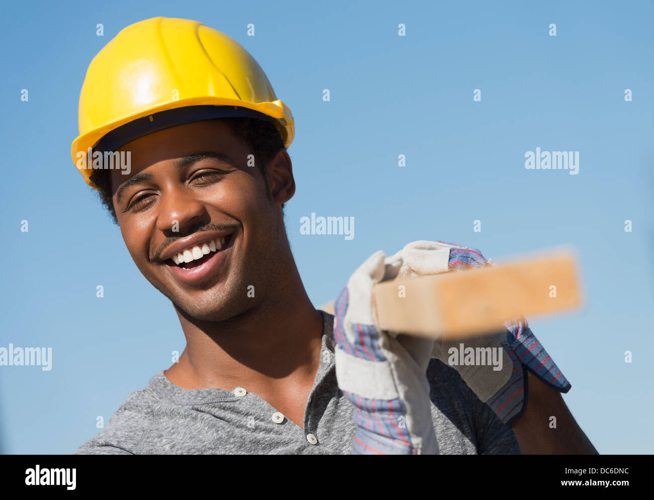 Construction worker carrying plank Stock Photo - Alamy