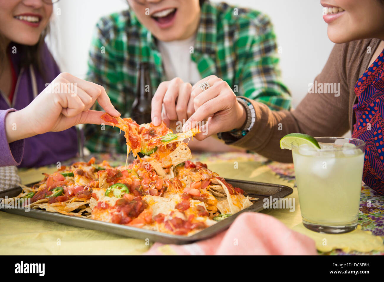 Young women and man eating nachos with melted cheese Stock Photo - Alamy