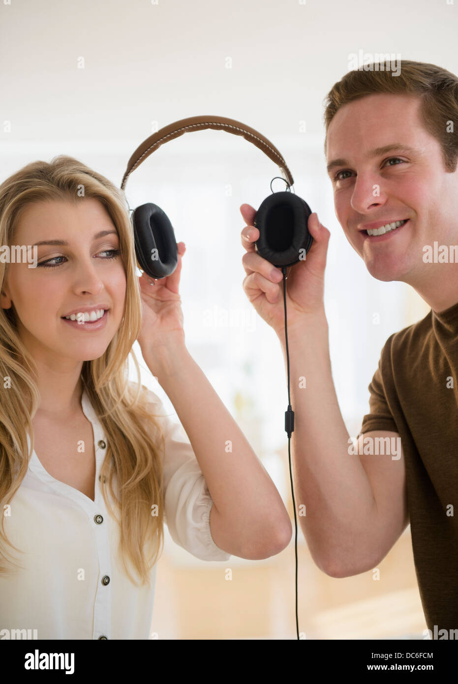 Couple using one headset together Stock Photo - Alamy