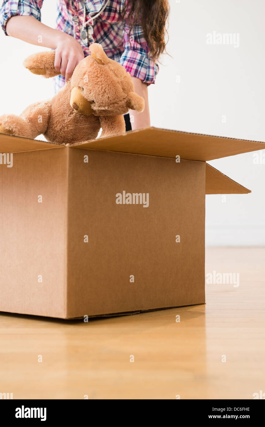 Girl (8-9) packing teddy bear to carton box Stock Photo - Alamy
