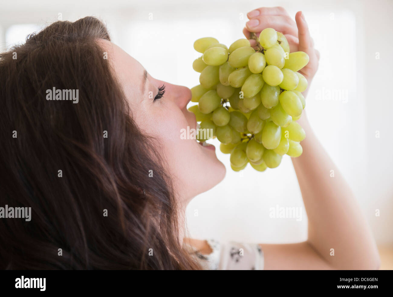 Portrait of young woman eating grapes Stock Photo - Alamy