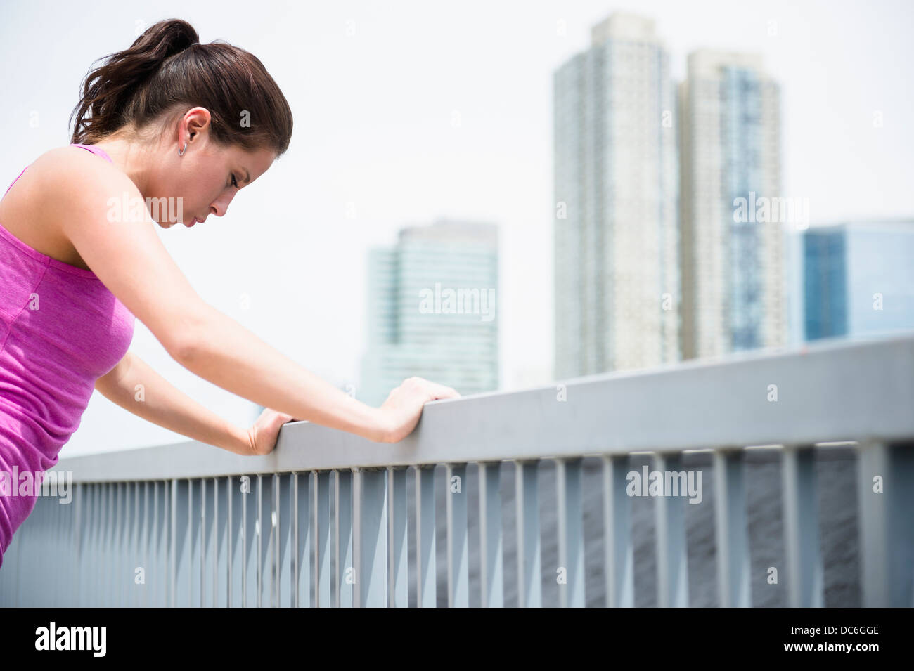 Young woman stretching by railing Stock Photo - Alamy