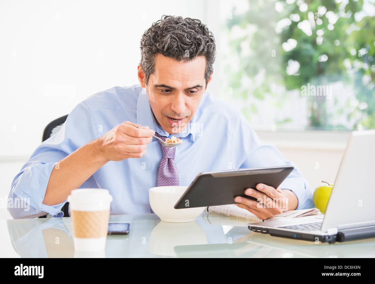 Portrait of man eating and using digital tablet Stock Photo - Alamy