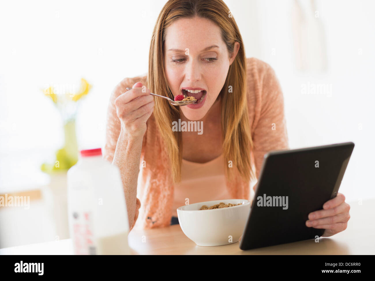 Woman eating breakfast and looking at tablet pc Stock Photo - Alamy