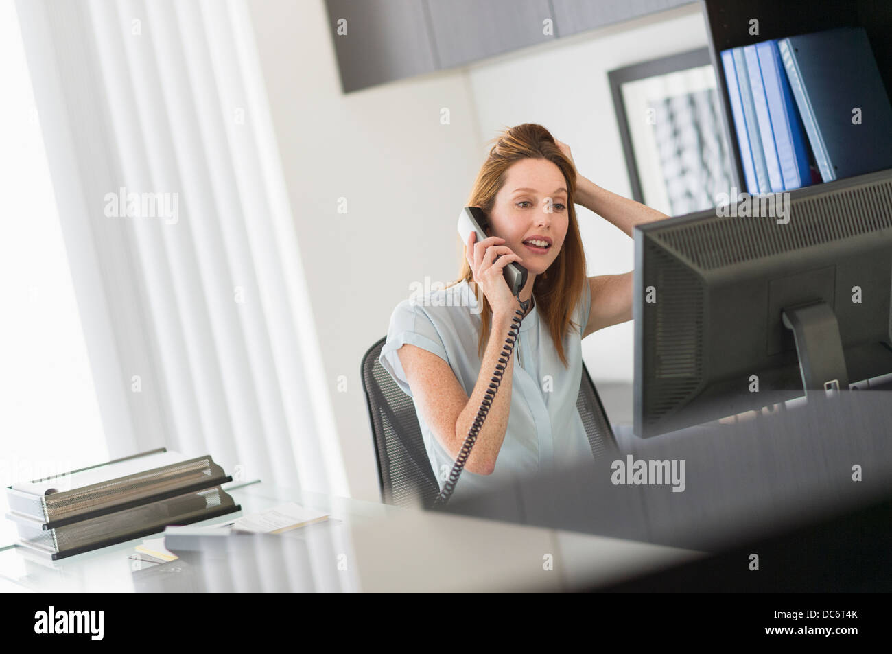 Business woman using computer and phone in office Stock Photo - Alamy