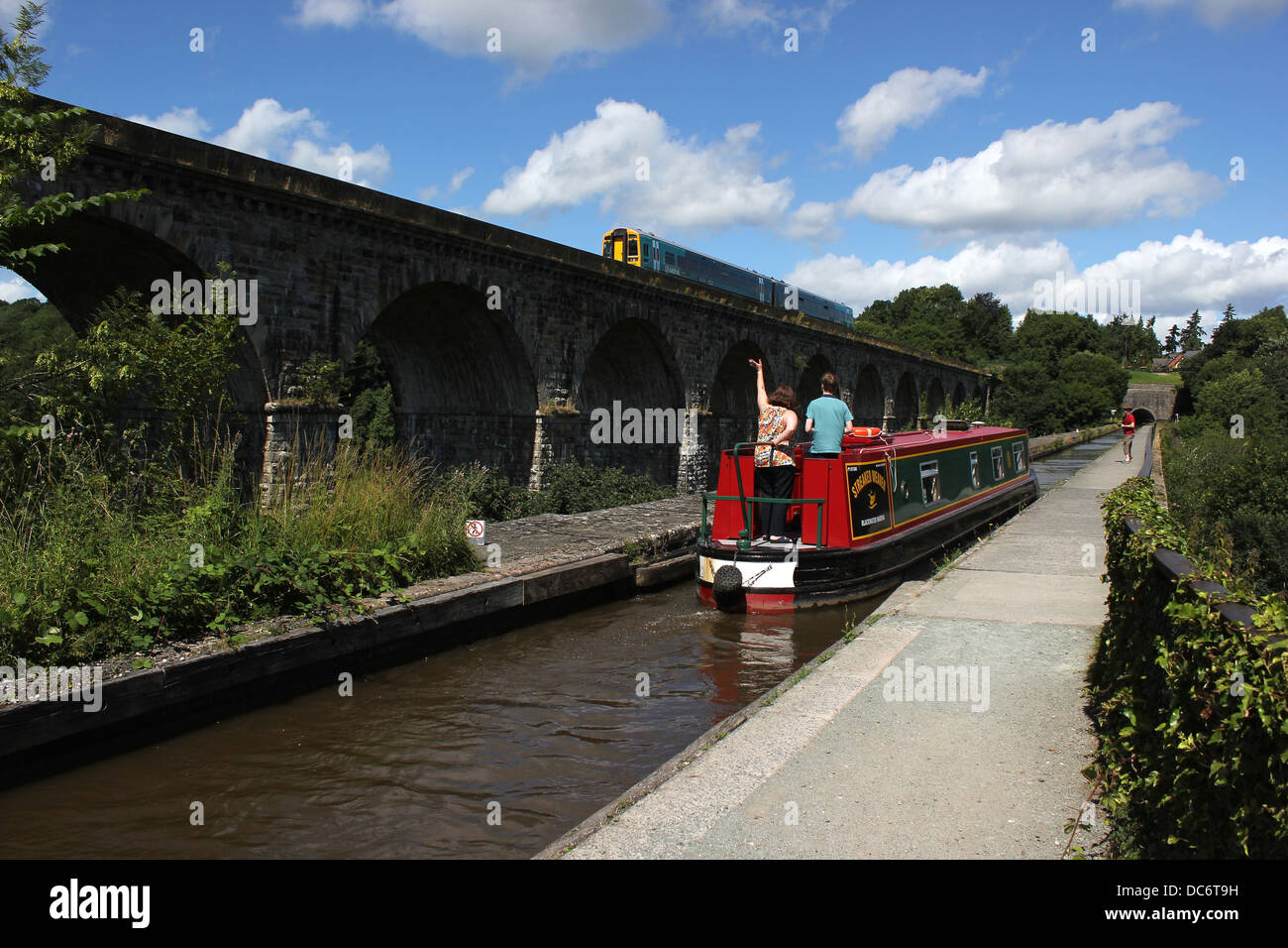 Woman on narrowboat waving at train Stock Photo - Alamy