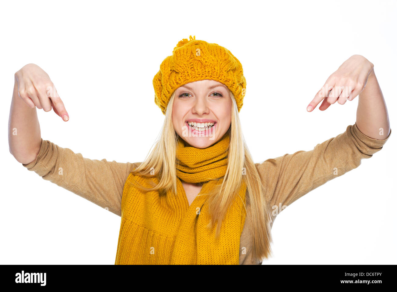 Smiling young woman in hat and scarf pointing down on copy space Stock ...