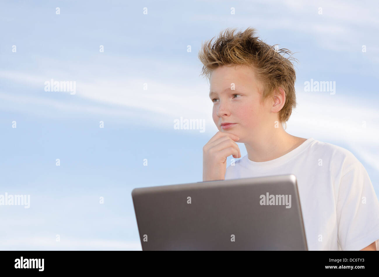 Serious schoolboy with mobile computer think about something on nature ...