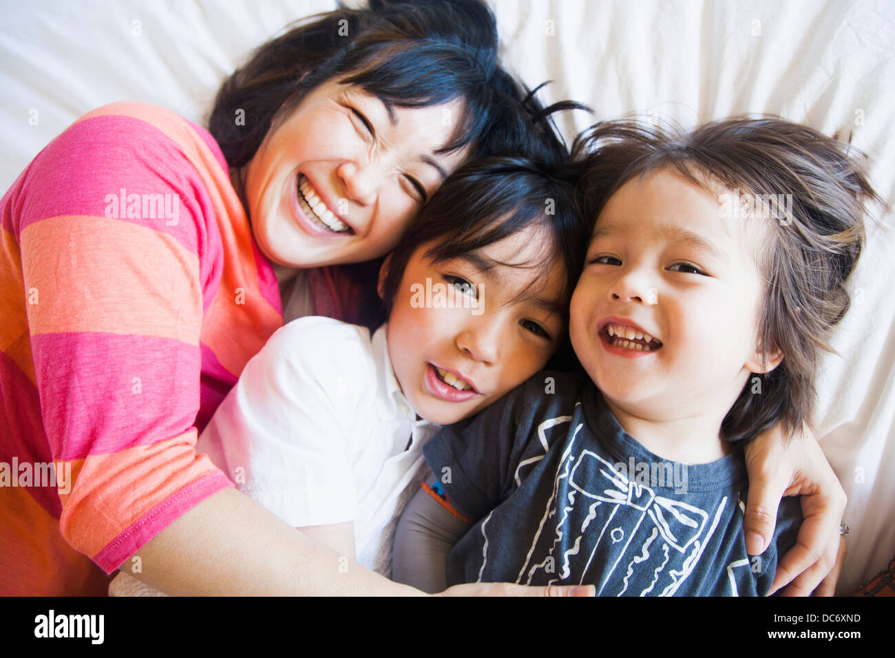Mother with children cuddling on bed Stock Photo - Alamy