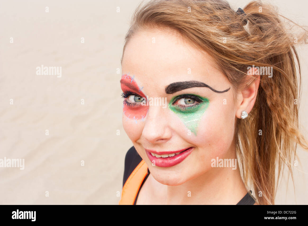 A close-up head shot of a young female circus performer with clown make ...